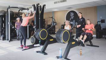 Uma academia com diversos equipamentos de exercícios, incluindo aparelho de cabo e esteiras.