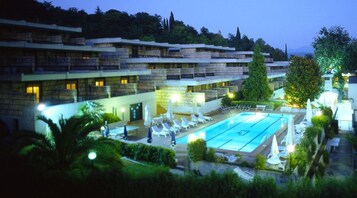 Um hotel com piscina, área de estar externa e montanhas ao fundo.