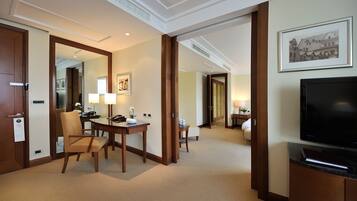 Quarto de hotel com área de jantar, televisão e quadro na parede.