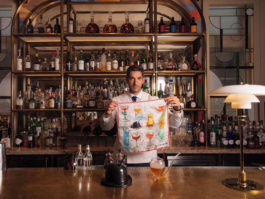 Bar com prateleiras cheias de garrafas de bebidas e uma pessoa segurando um cardápio.