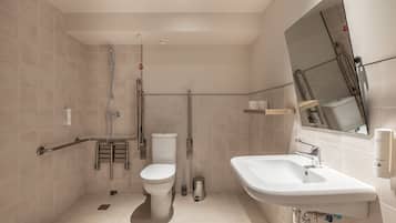 Casa de banho moderna com sanita, bidé e lavatório, equipada com barras de apoio e corrimão.