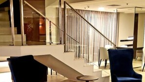 Um hall de hotel moderno com escadaria, área de estar e vista para o exterior.