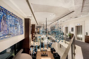 Um saguão moderno com um grande mural azul, um candelabro e uma área de estar.
