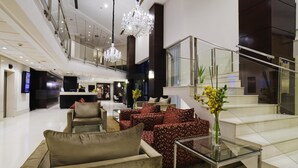 Um hall amplo com design moderno, com uma mesa de centro de vidro, assentos confortáveis e uma escadaria.