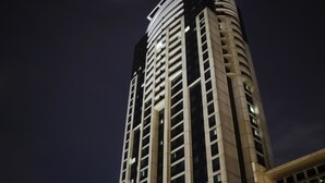 Um edifício alto com vários andares, design arquitetônico moderno e uma área de entrada bem iluminada.
