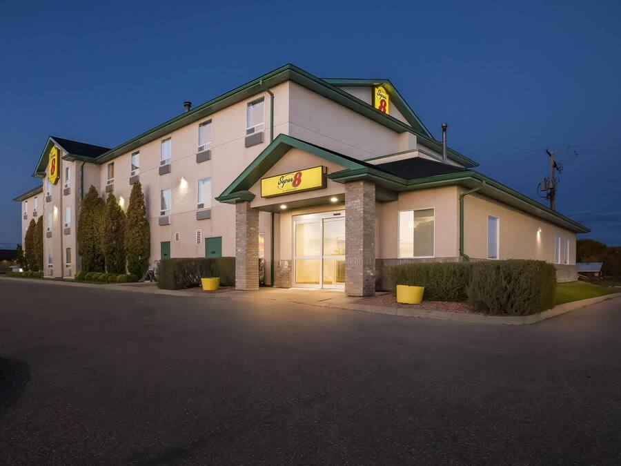 Um hotel com um letreiro grande com o número 8, várias janelas e uma entrada bem iluminada.