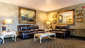 Quarto de hotel com sofá de couro, uma mesa de centro e um espelho grande.