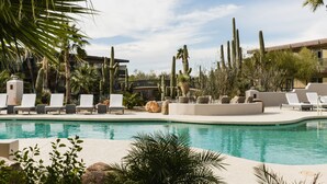 Uma área de piscina com espreguiçadeiras e cactos.