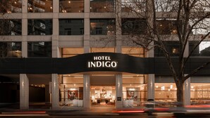 Uma entrada de hotel moderna com uma placa destacada que diz 'HOTEL INDIGO'.