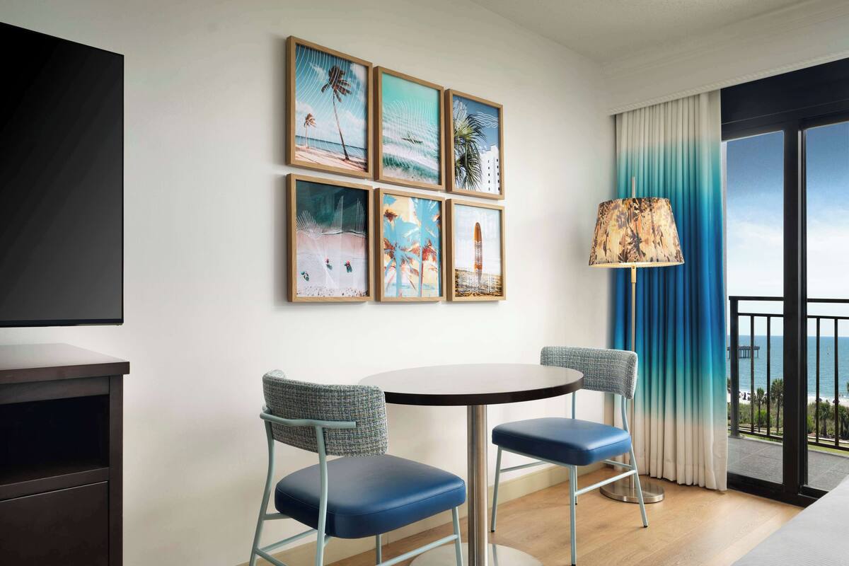 Quarto de hotel moderno com varanda, televisão e obras de arte na parede.