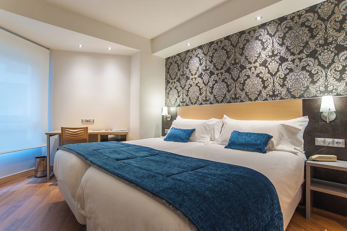 Quarto de hotel com uma cama grande, uma mesa e uma cadeira.