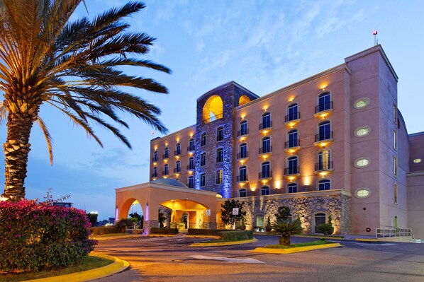 Um hotel grande com vários andares, um pátio central e uma arcada imponente.