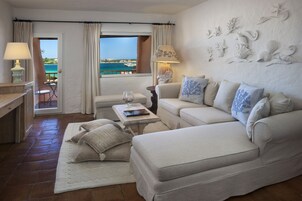 Sala de estar com sofá, mesa de centro e vista para o mar pela janela.
