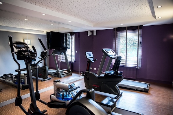Uma academia moderna com equipamentos de cardio, espelho e amplas janelas.