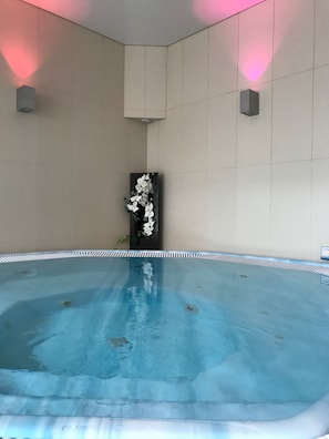 Piscina com piso azulejado e parede decorada com flores.