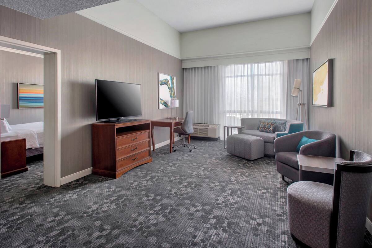 Quarto de hotel com uma cama, uma mesa com televisão, um sofá e uma cadeira.