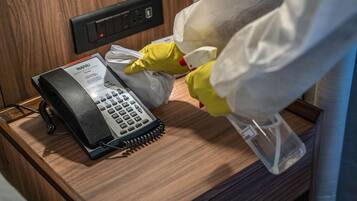 Quarto de hotel com uma secretária de madeira, um telefone e um saco plástico.