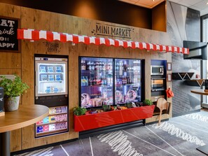 Um pequeno mercado com balcões refrigerados, micro-ondas e máquina de café.