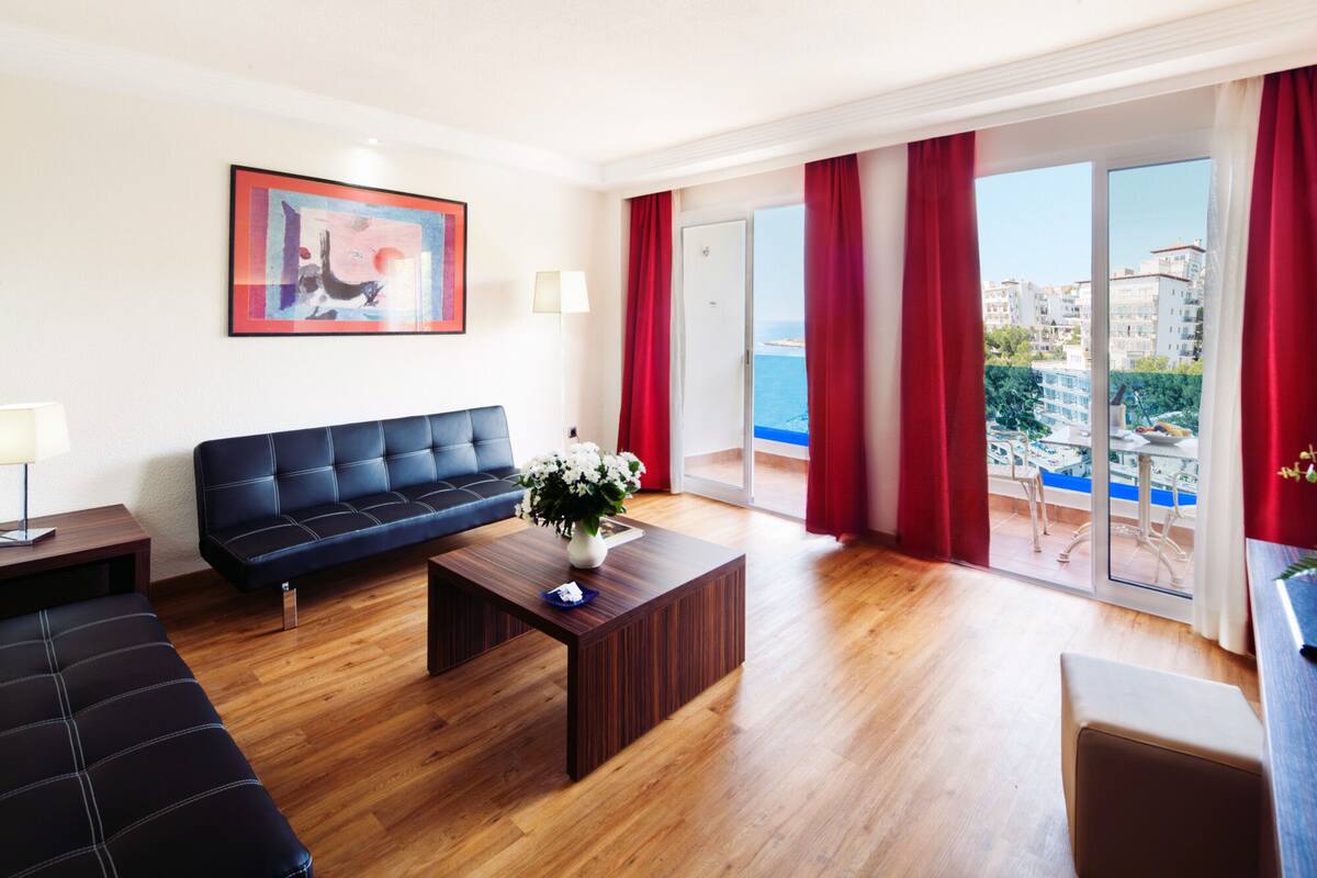 Uma sala de estar moderna com um sofá preto, mesa de centro de madeira e um quadro na parede.