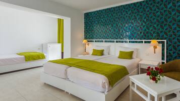 Quarto de hotel com duas camas, uma escrivaninha branca e uma mesa com flores.