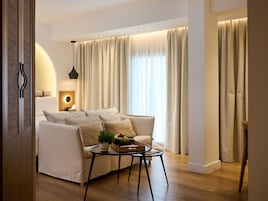 Uma sala de estar moderna com um sofá, uma mesinha com uma planta e uma luminária.