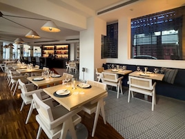 Um restaurante com várias mesas, cadeiras e um espaço de bar.