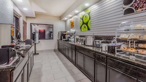 Uma cozinha moderna com uma bancada comprida, equipada com diversos eletrodomésticos e um espaço para café.