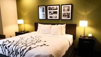 Quarto de hotel com uma cama, duas mesas de cabeceira e três quadros na parede.