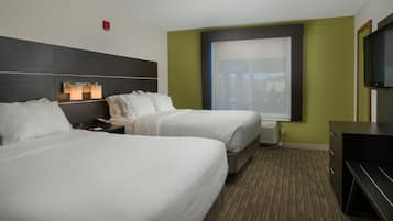 Quarto de hotel com duas camas, televisão, escrivaninha e janela com persianas.