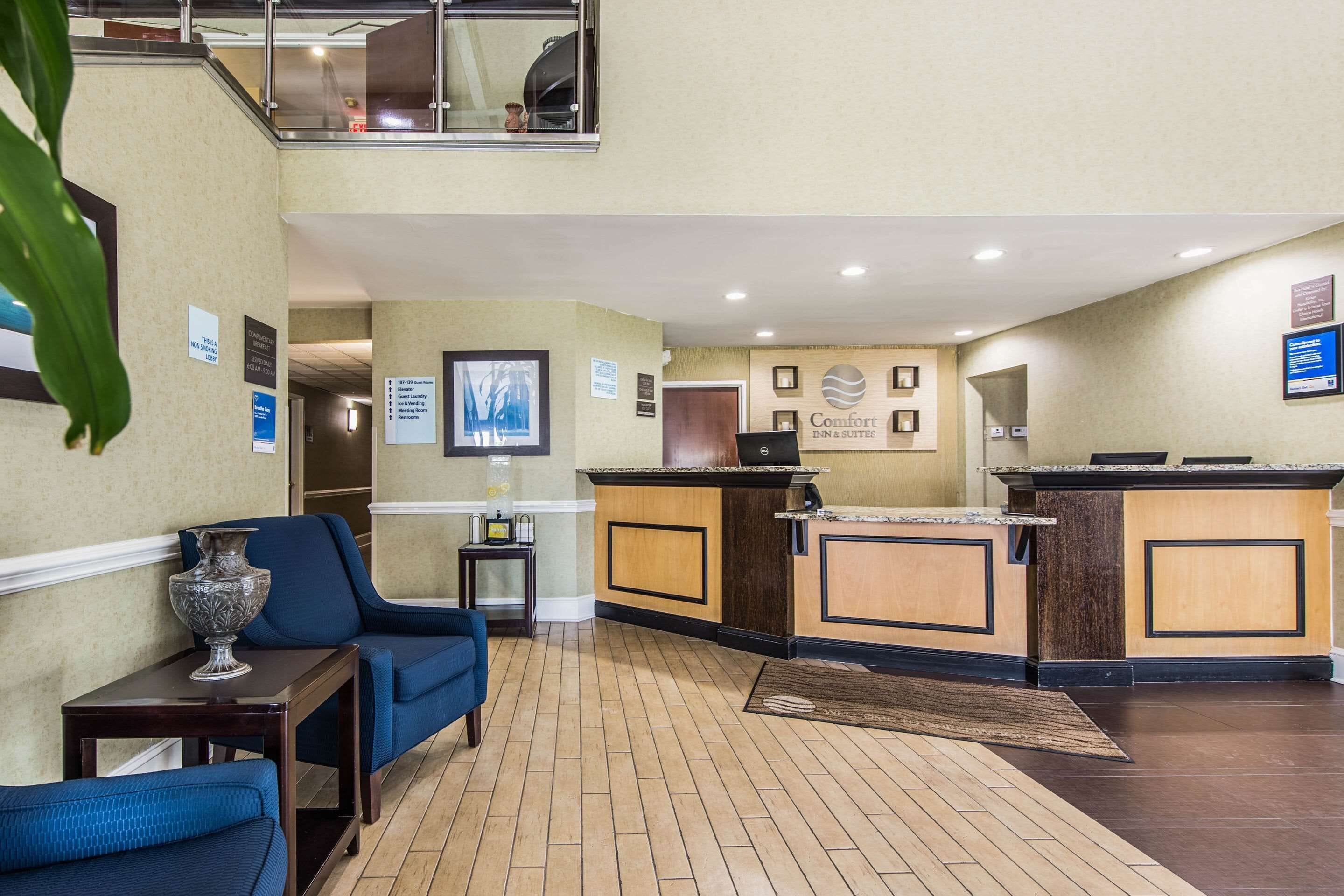 Um saguão de hotel com balcão de recepção, área de estar e escadaria.