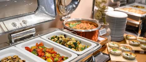 Buffet com diversas opções de comida, incluindo legumes e cogumelos.