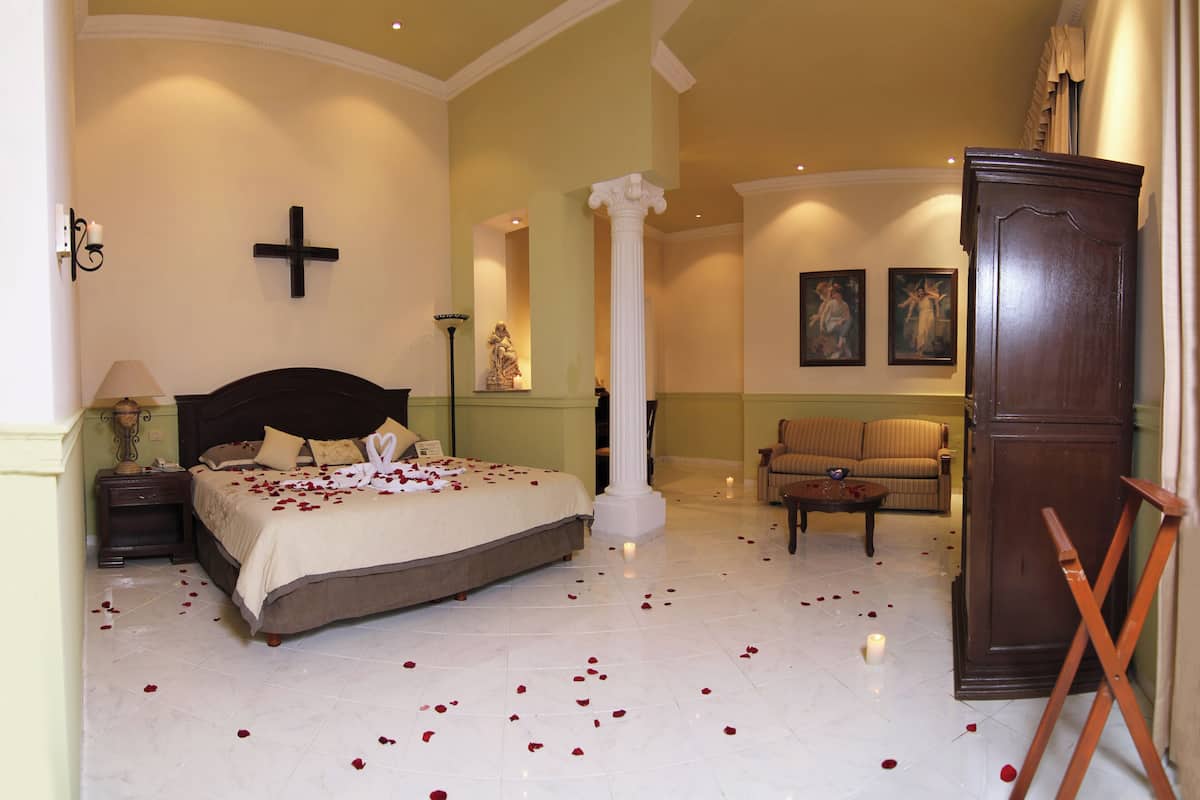 Um quarto espaçoso com uma cama grande, um sofá, um armário e um quadro na parede.