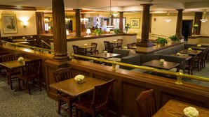 Um restaurante com mesas e cadeiras de madeira, um balcão e uma área de estar com um sofá.