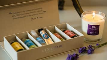 Uma caixa de produtos L'OCCITANE, uma vela com a etiqueta 'White Lily & Gardenia' e uma frase na caixa.