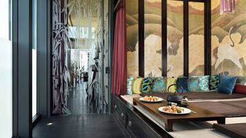 Um quarto com porta japonesa tradicional deslizante, uma mesa de jantar com um prato de comida e um sofá com almofadas coloridas.