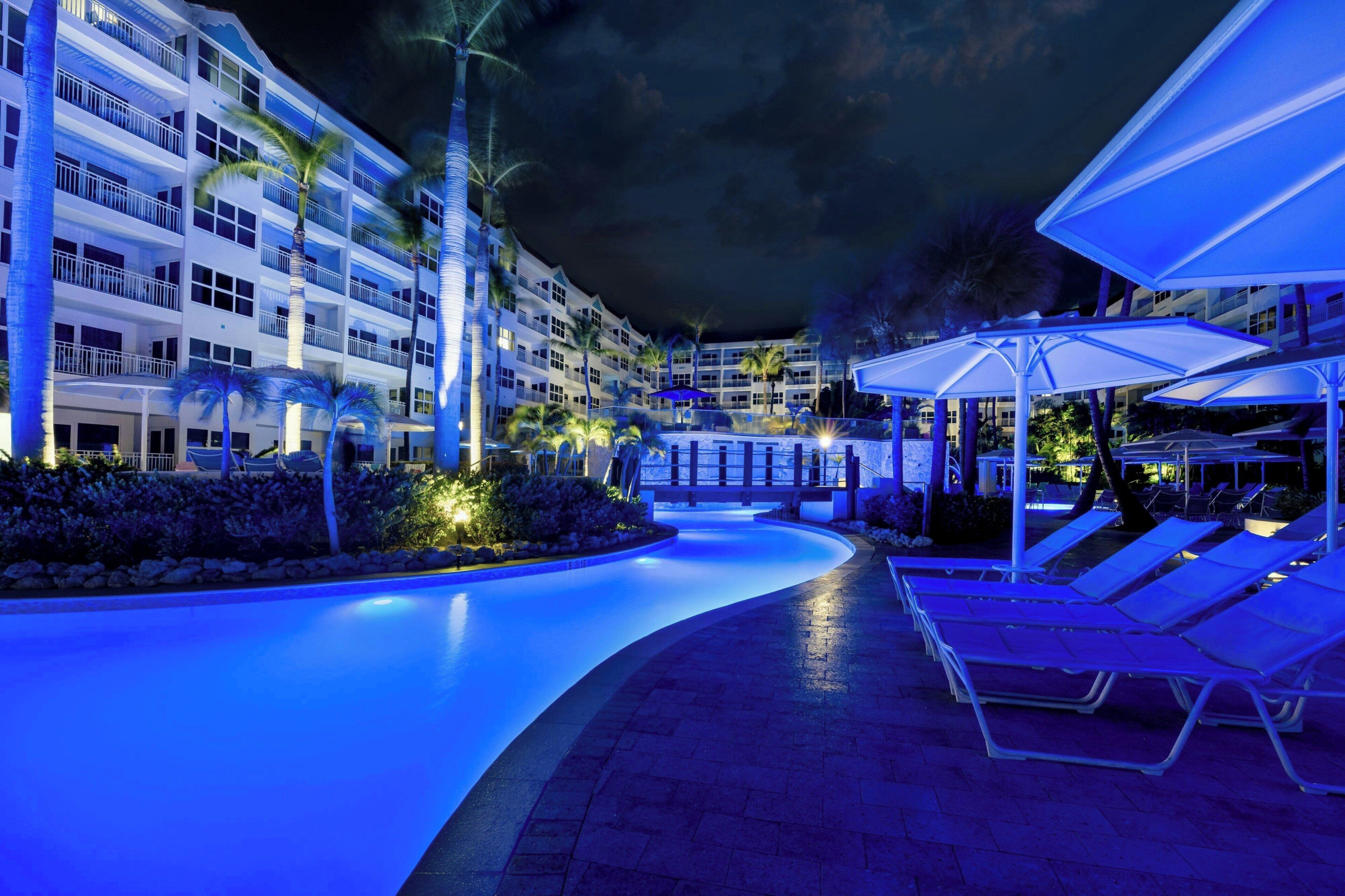 Área de piscina de hotel com piscina sinuosa, espreguiçadeiras e guarda-sóis.
