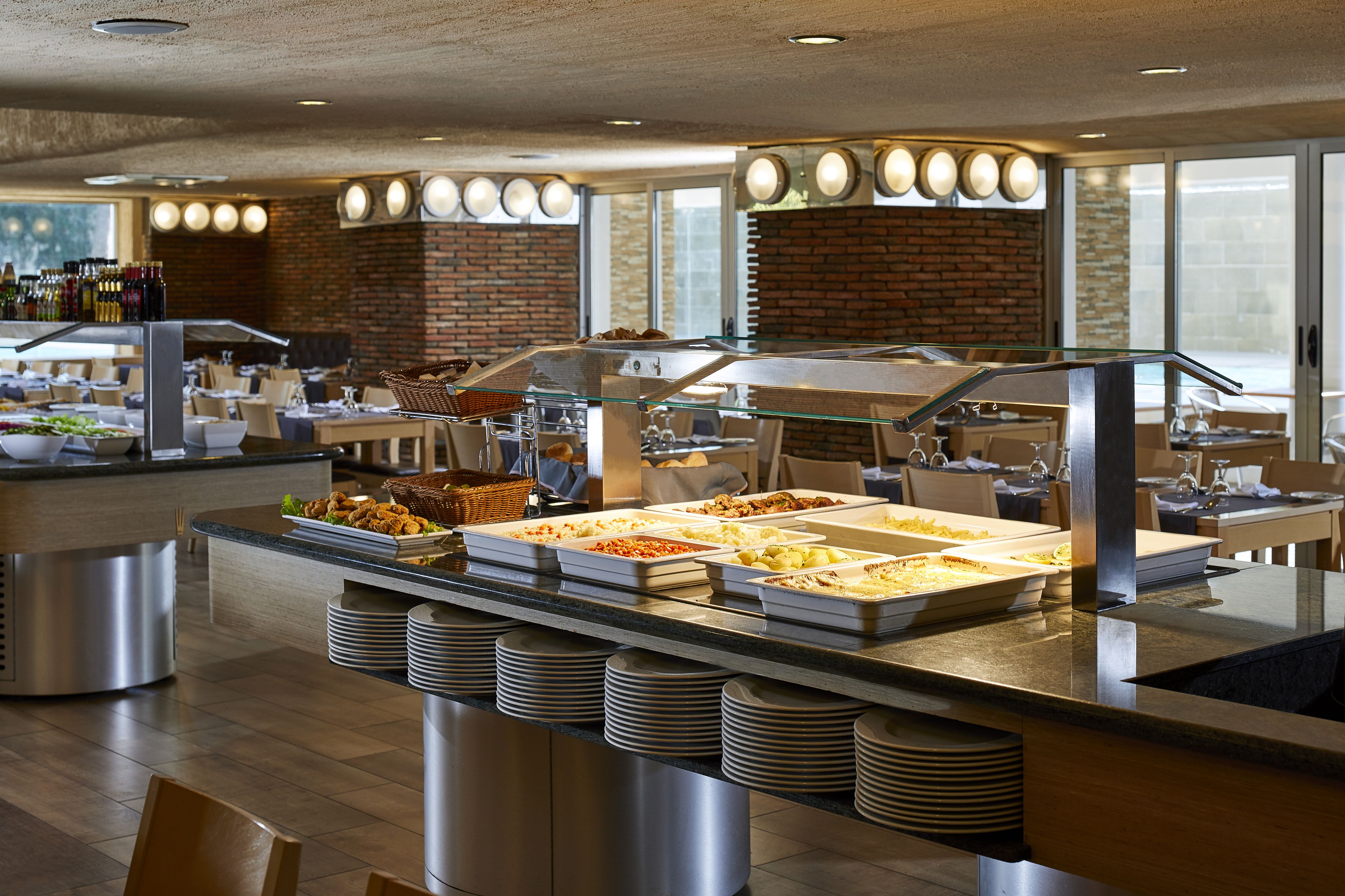 Disposição de buffet com diversos alimentos e um expositor de vidro.