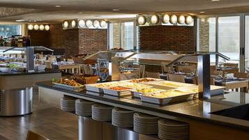 Disposição de buffet com diversos alimentos e um expositor de vidro.