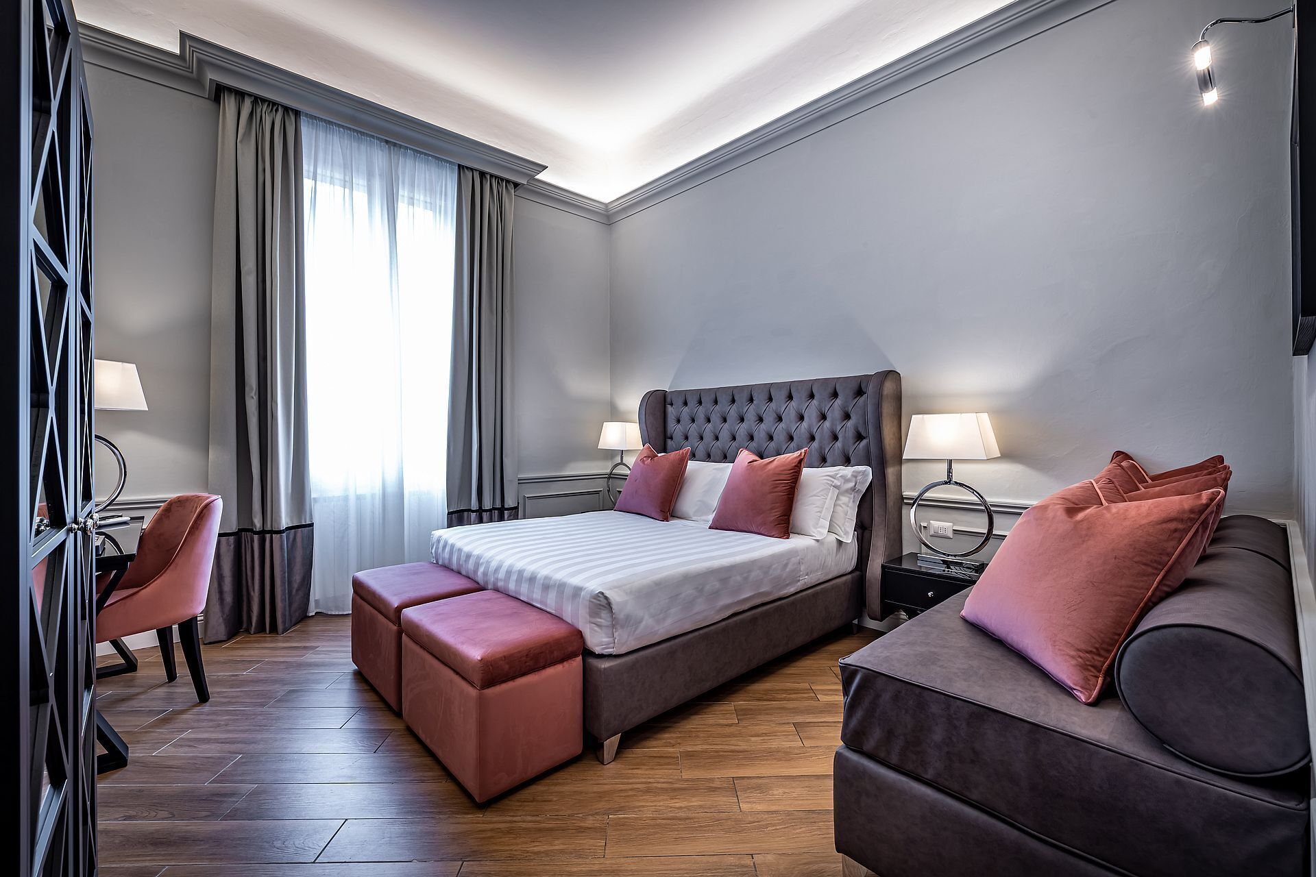 Quarto de hotel moderno com uma cama grande, um sofá, uma escrivaninha e uma cadeira.