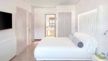 Quarto de hotel moderno com cama grande, televisão de tela plana, piso de madeira e vista para o banheiro.