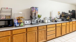 Cozinha equipada com micro-ondas, torradeira, máquina de café e diversos eletrodomésticos.