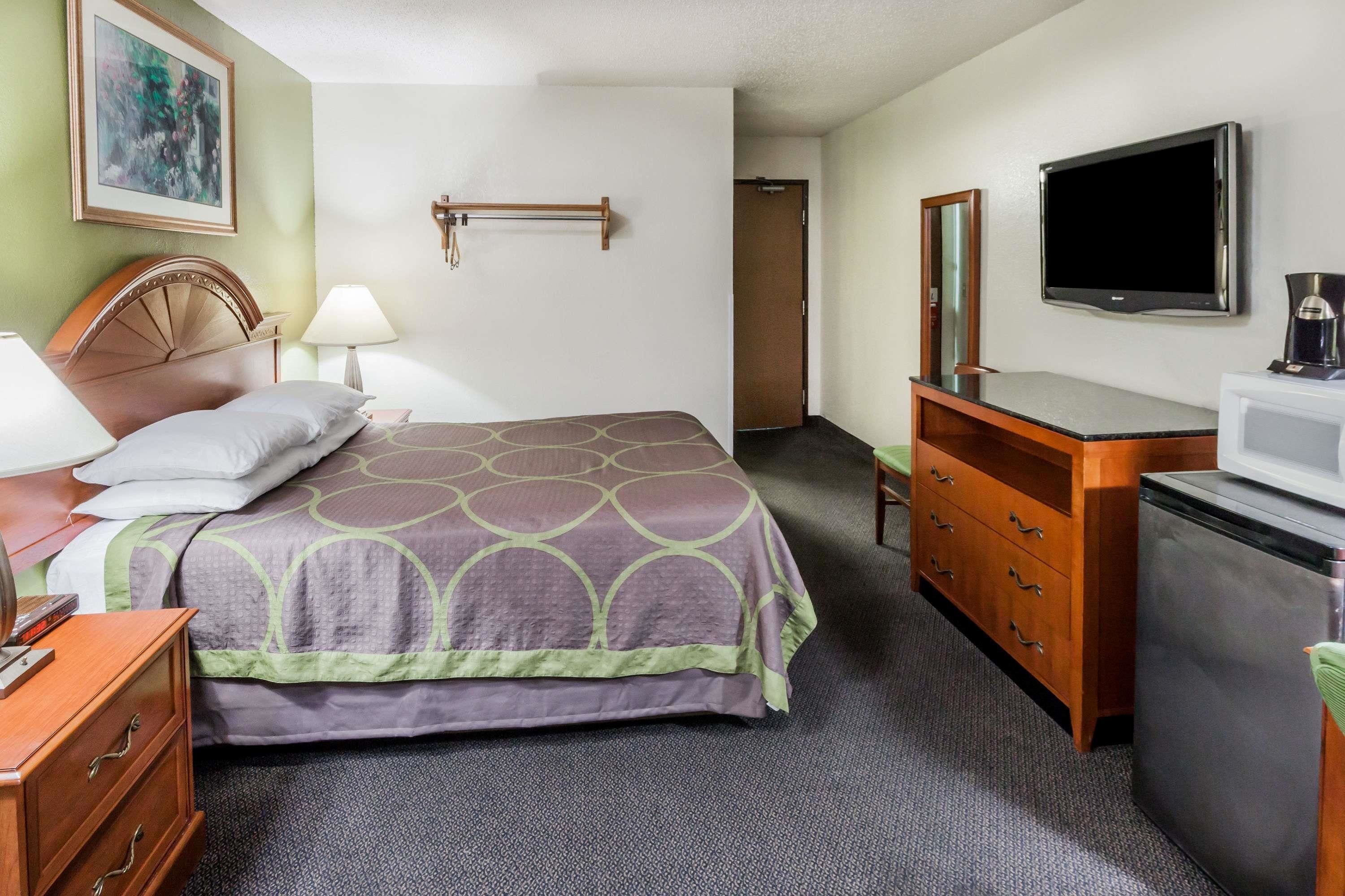 Quarto de hotel com cama, cômoda, televisão e micro-ondas.