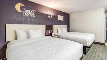 Quarto de hotel com duas camas, uma mesinha de cabeceira, um relógio de parede e um letreiro que diz 'Sonhos Doces'.