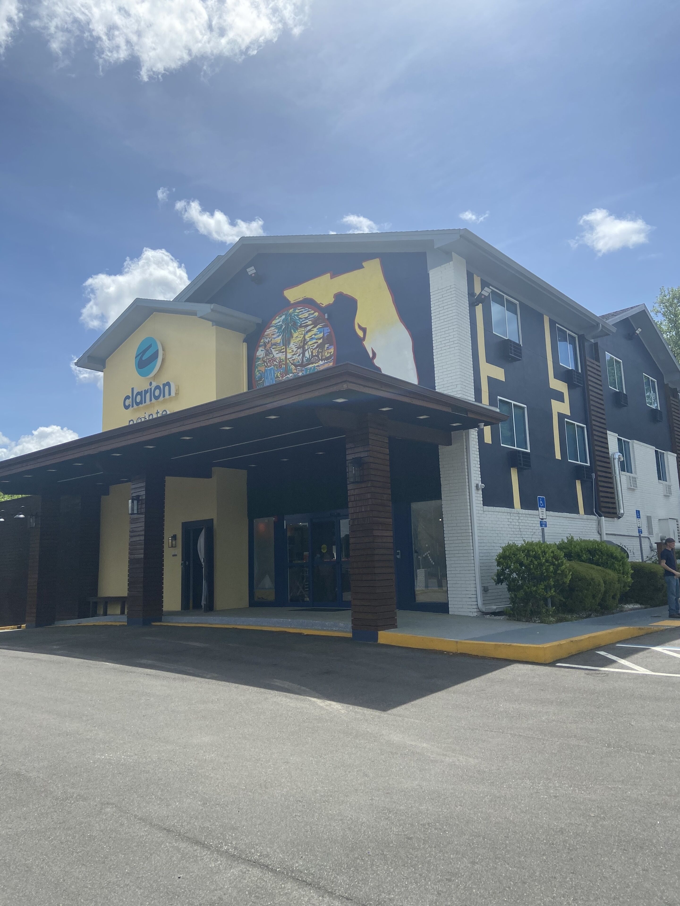 Um hotel Clarion com um mural distinto na fachada, uma entrada coberta e um estacionamento.