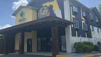 Um hotel Clarion com um mural distinto na fachada, uma entrada coberta e um estacionamento.