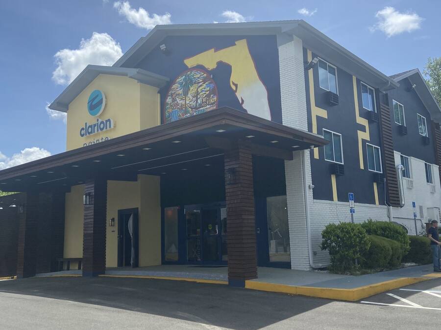 Um hotel Clarion com um mural distinto na fachada, uma entrada coberta e um estacionamento.