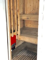 Uma sauna com paredes de madeira e chão de grade de metal.