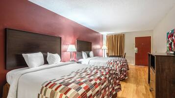 Quarto de hotel com duas camas, cabeceira de madeira, escrivaninha e um quadro na parede.
