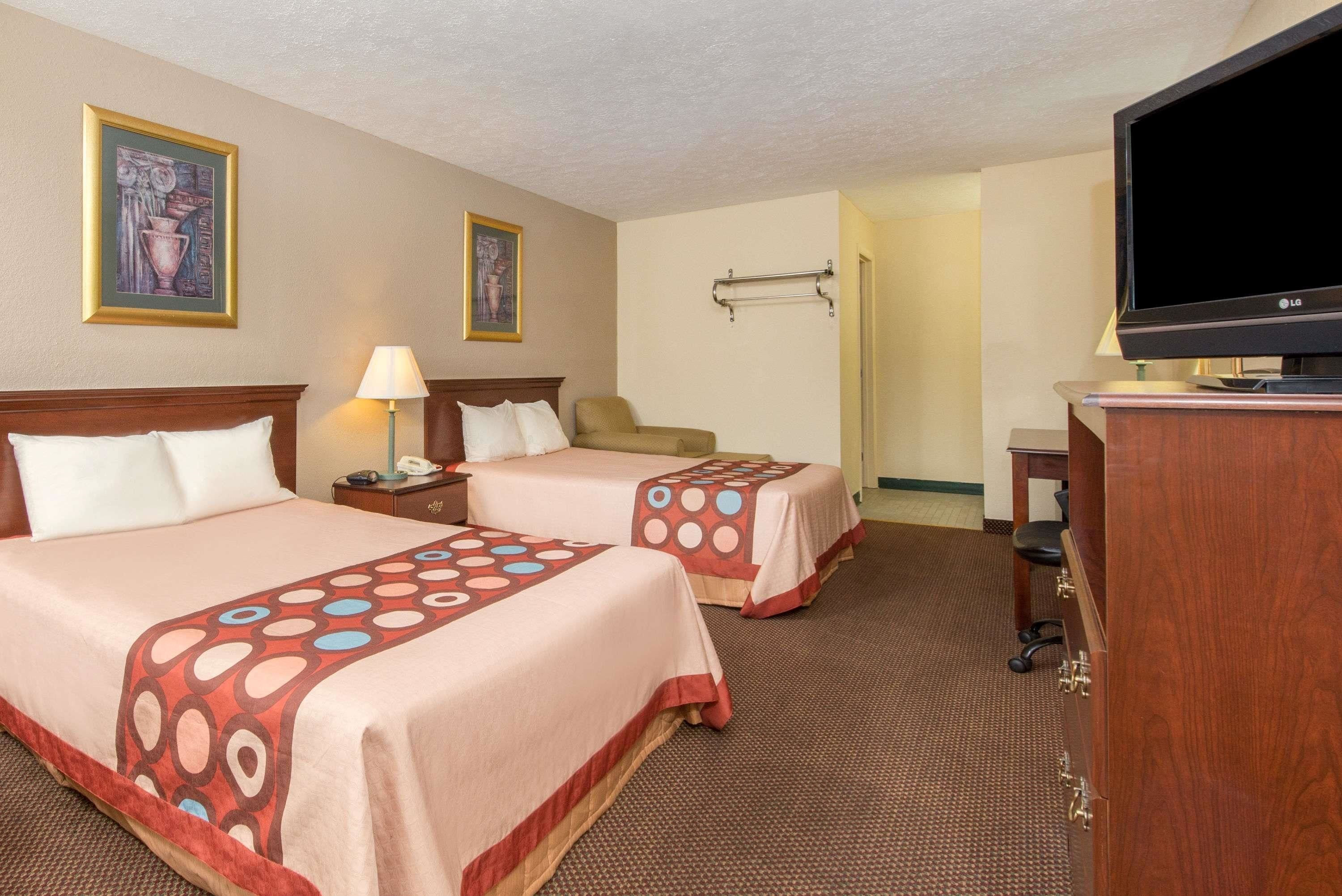 Quarto de hotel com duas camas, televisão, escrivaninha e cadeira.