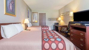 Quarto de hotel com duas camas, uma escrivaninha, televisão e cómoda.
